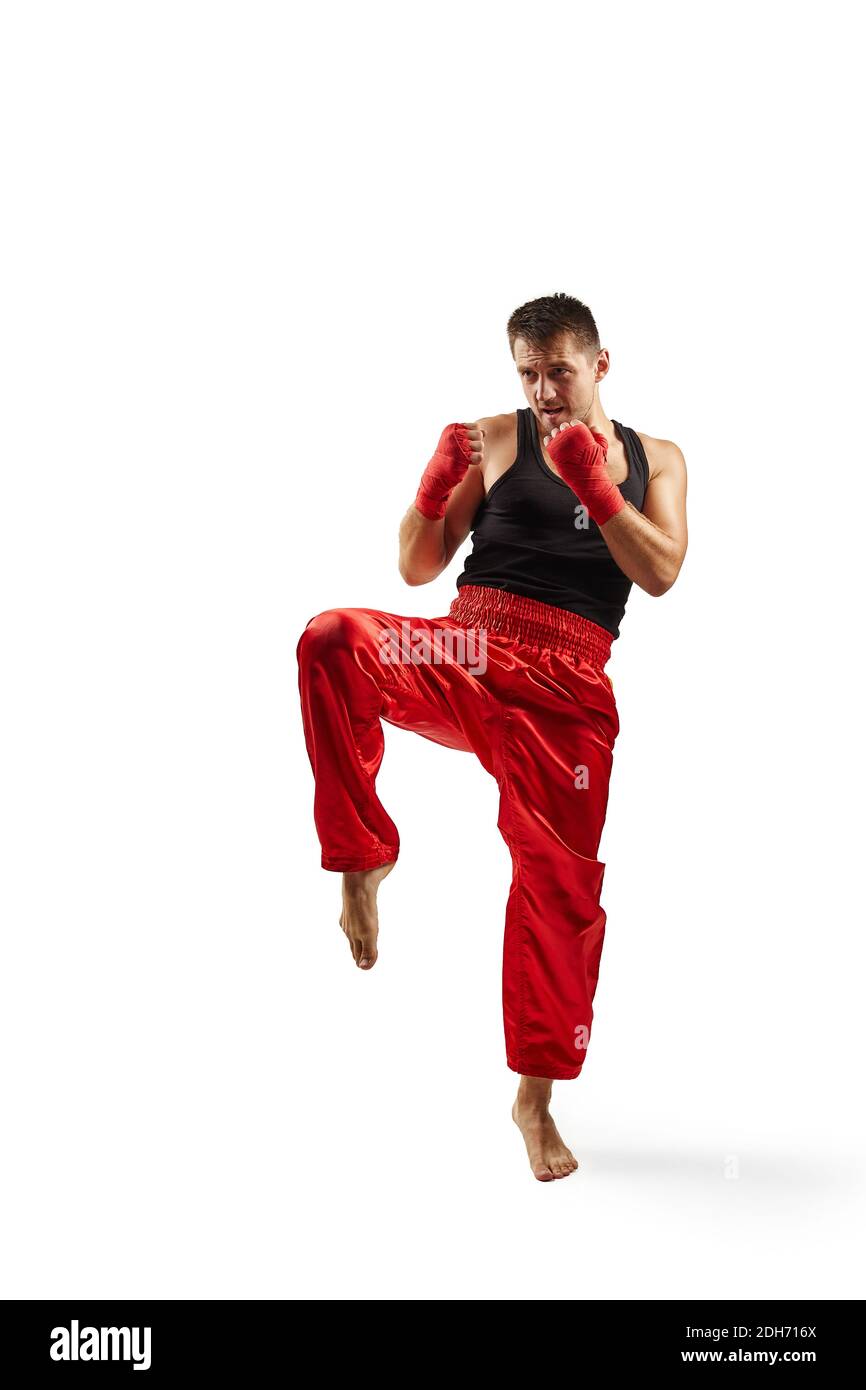 Athletic man in red sports bandages on his hands making kick during ...