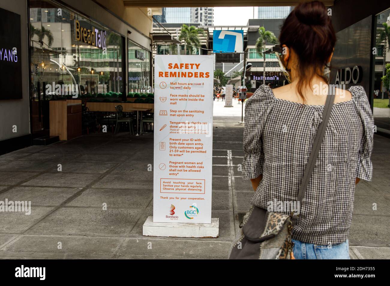 Dec 8, 2020 Woman reading safety signs at Bonifacio High street, Makati ...