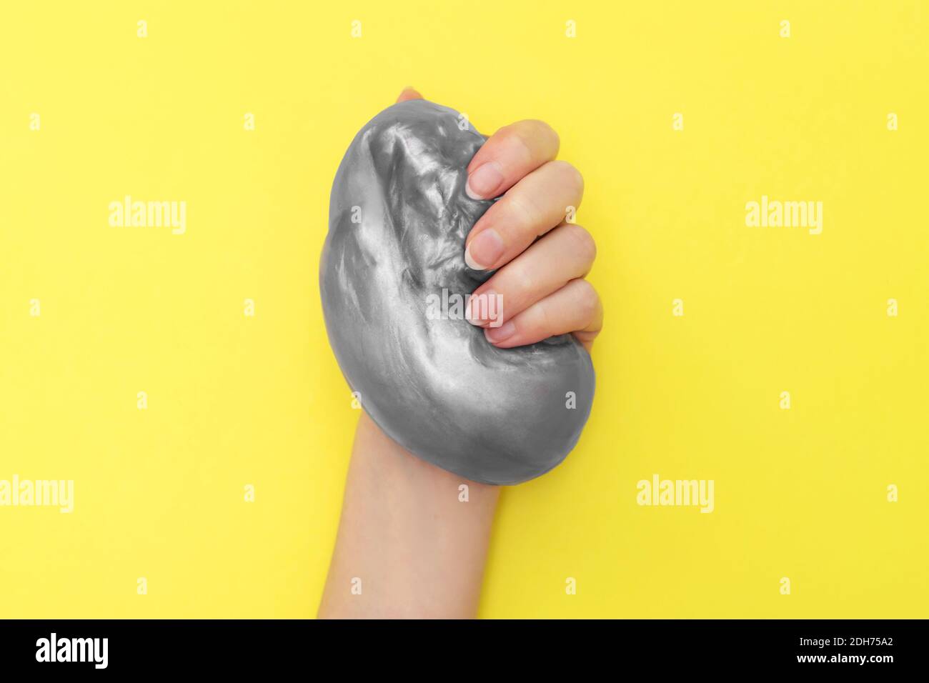 Gray slime in hand on yellow background. Kids play Stock Photo - Alamy