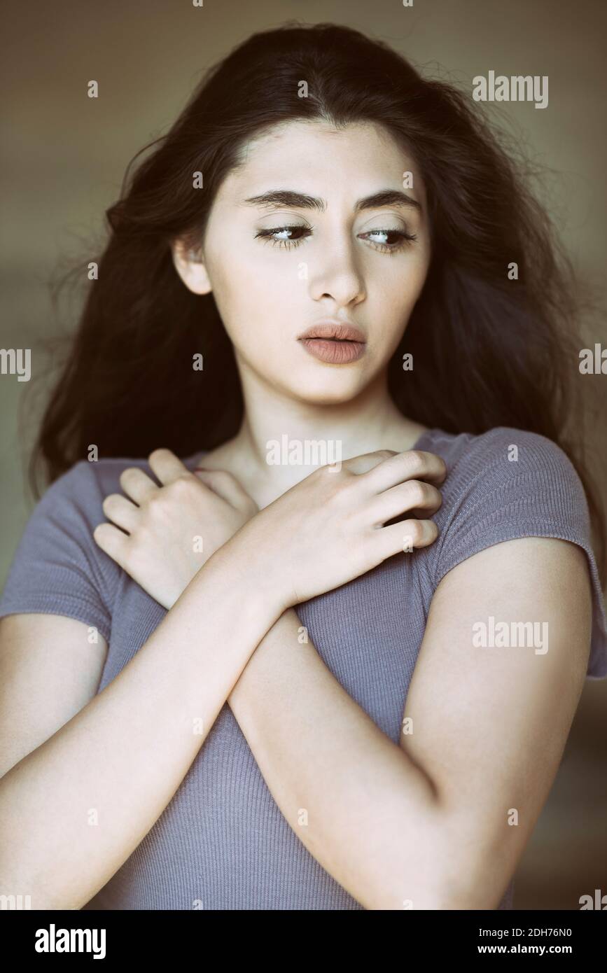 Beautiful young woman hands over heart looking away Stock Photo - Alamy