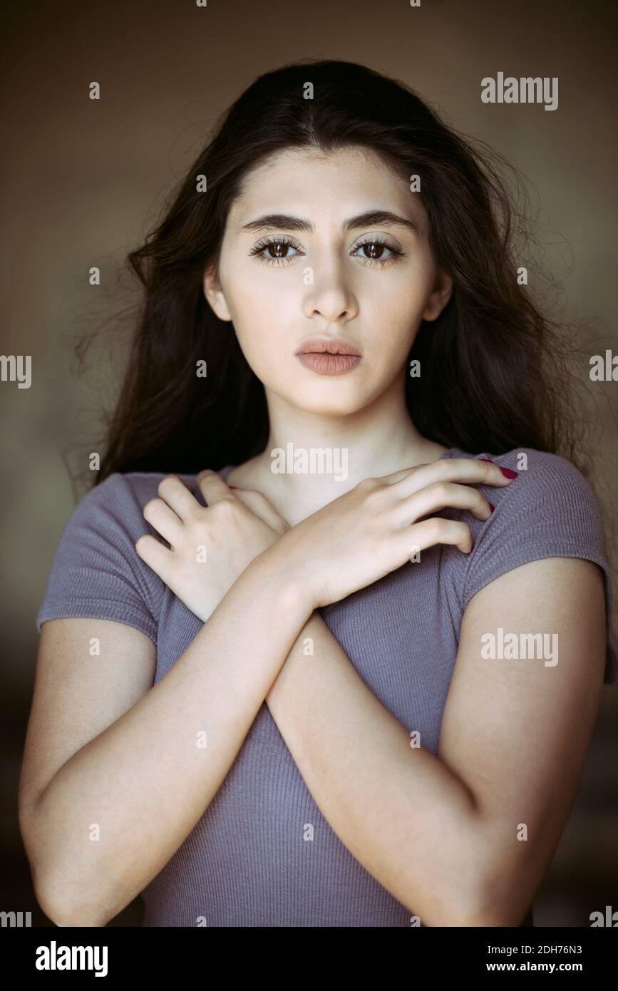 Beautiful young woman hands over heart looking away Stock Photo - Alamy