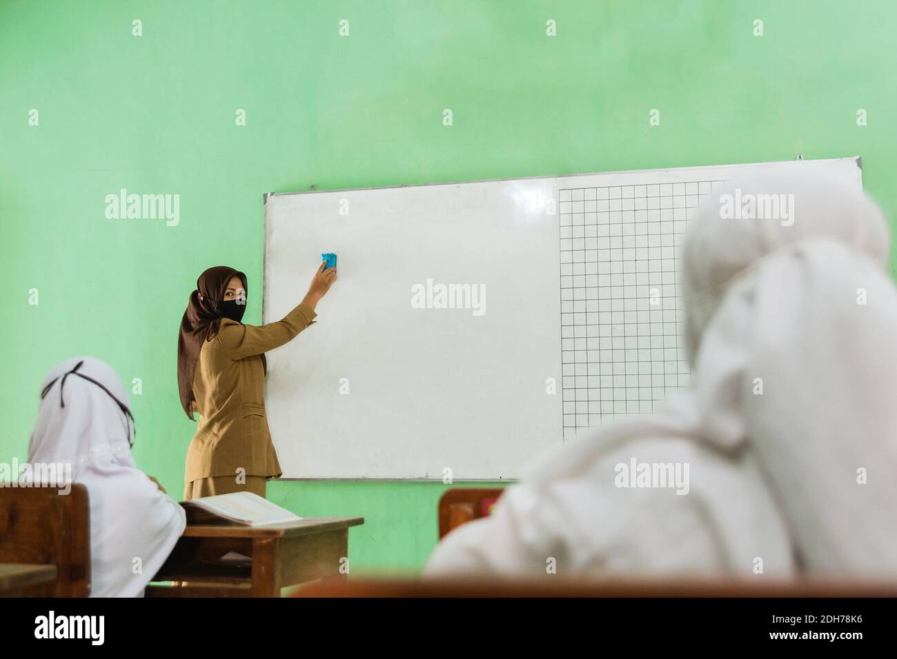 a teacher is explaining a lesson in front of the class to her students ...