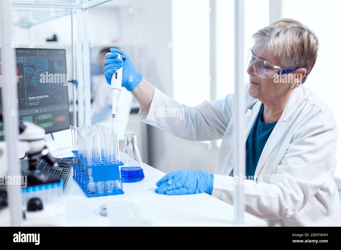 Senior scientist in modern facility conducting experiment using ...