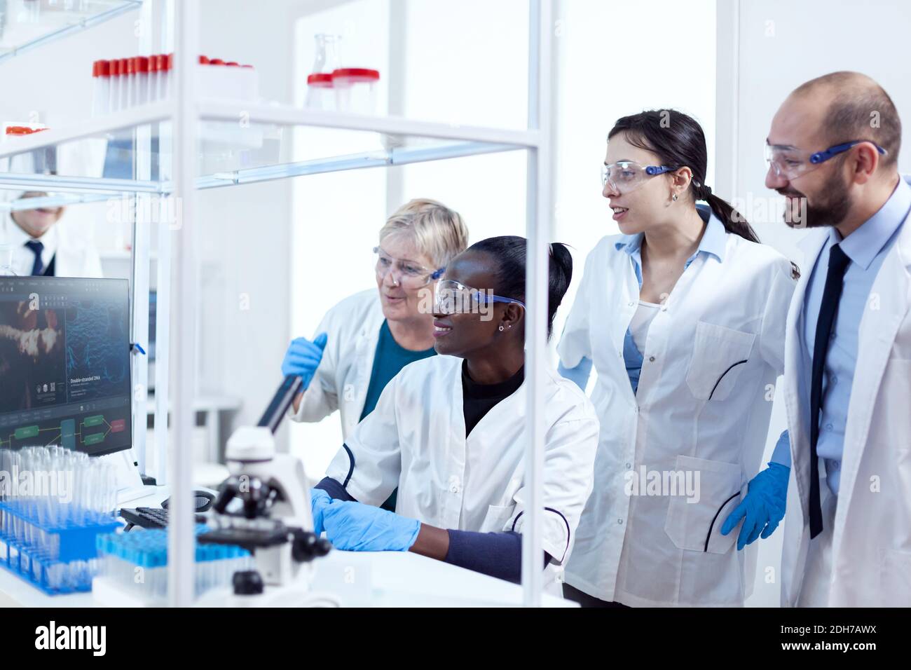 Group of multiethnic pharmacy scientists in lab coats working together in modern facility. Black ...