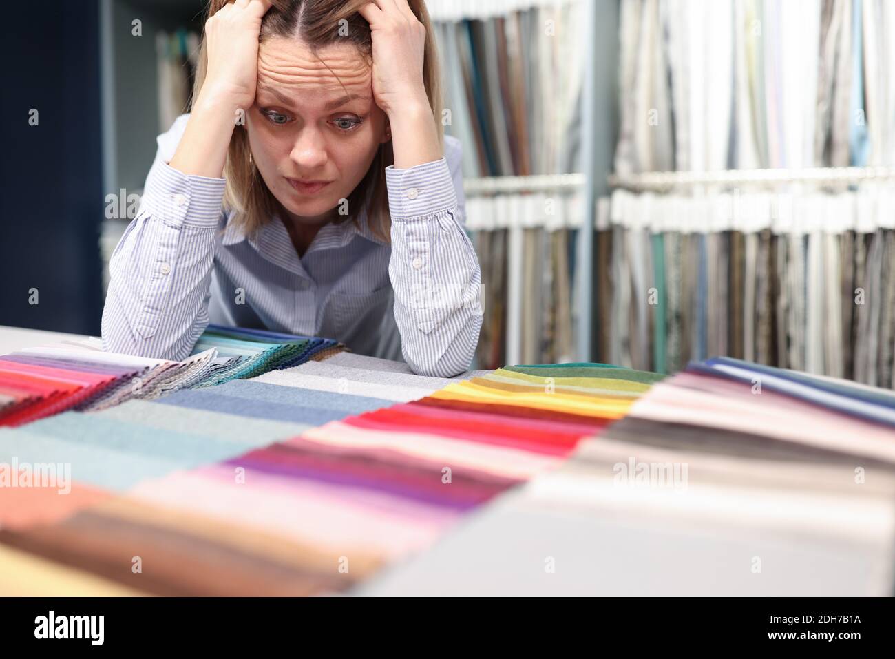 Confused woman chooses fabrics in t store Stock Photo - Alamy