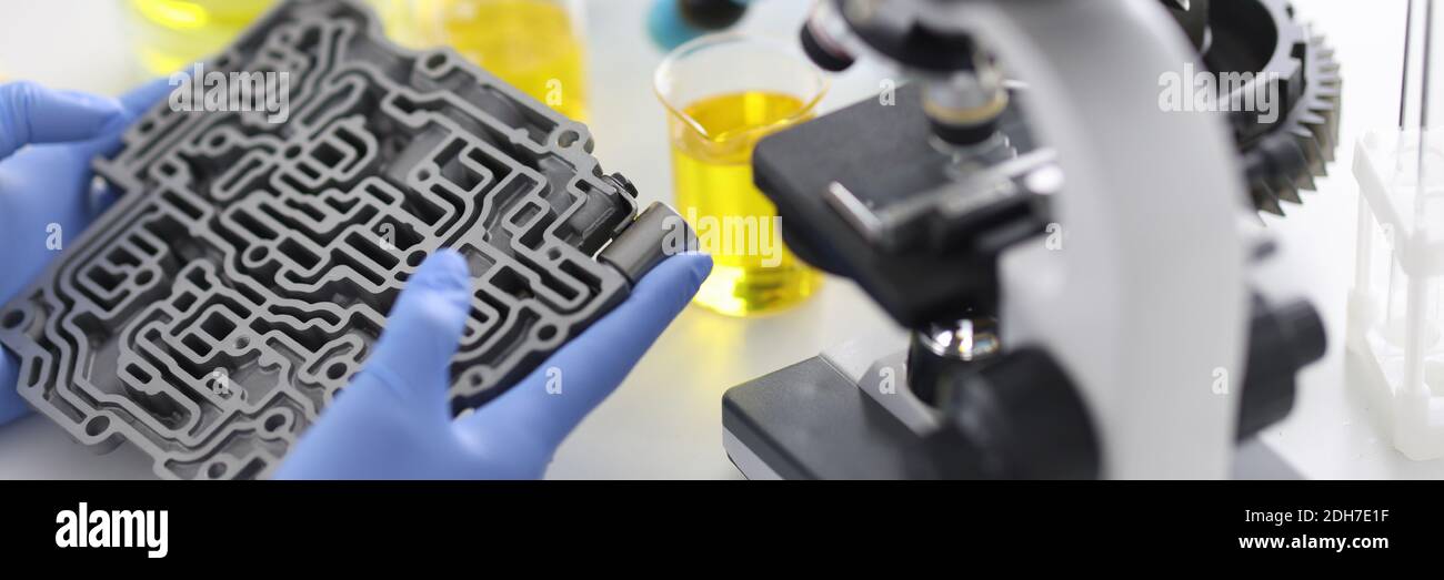 Automatic transmission lies in rubber gloves on table with microscope ...