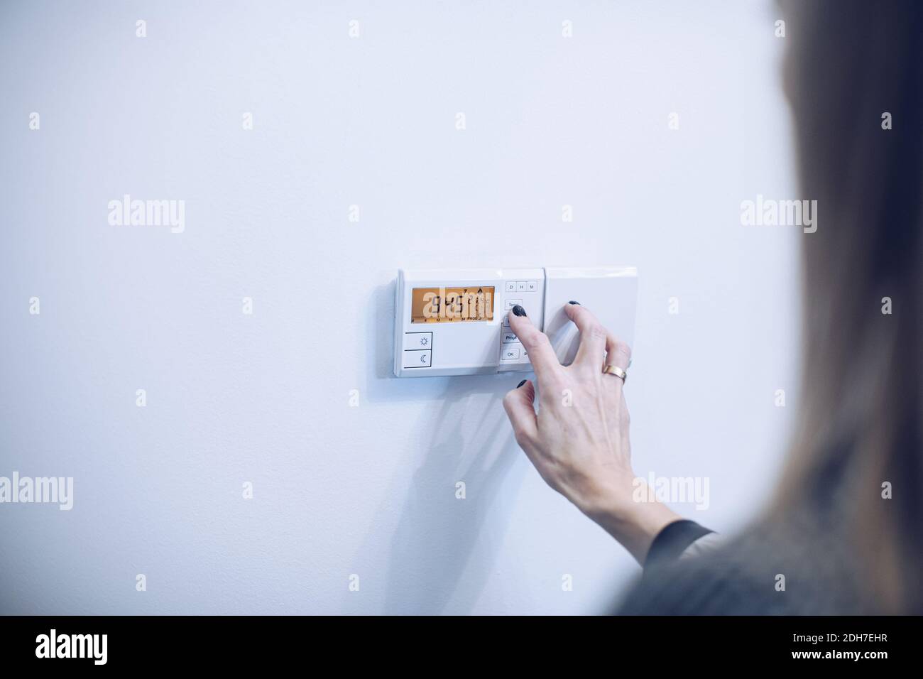 Woman adjusting temperature on home heating control Stock Photo - Alamy