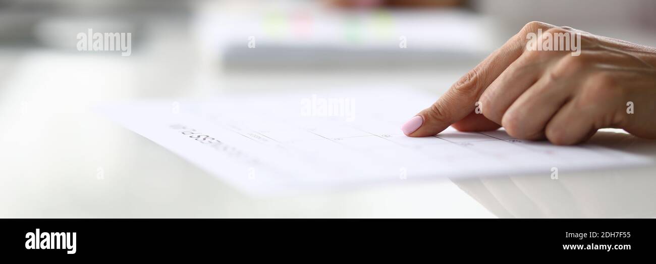 Female hand points finger at line in document at table in office ...