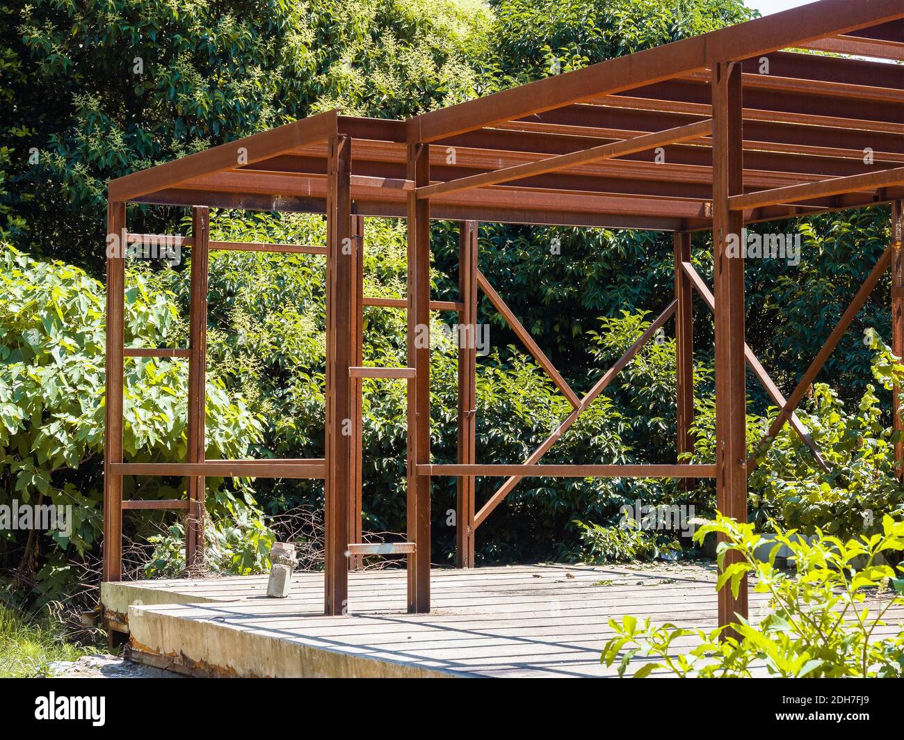 A metal structure standing on a concrete slab among the trees ...