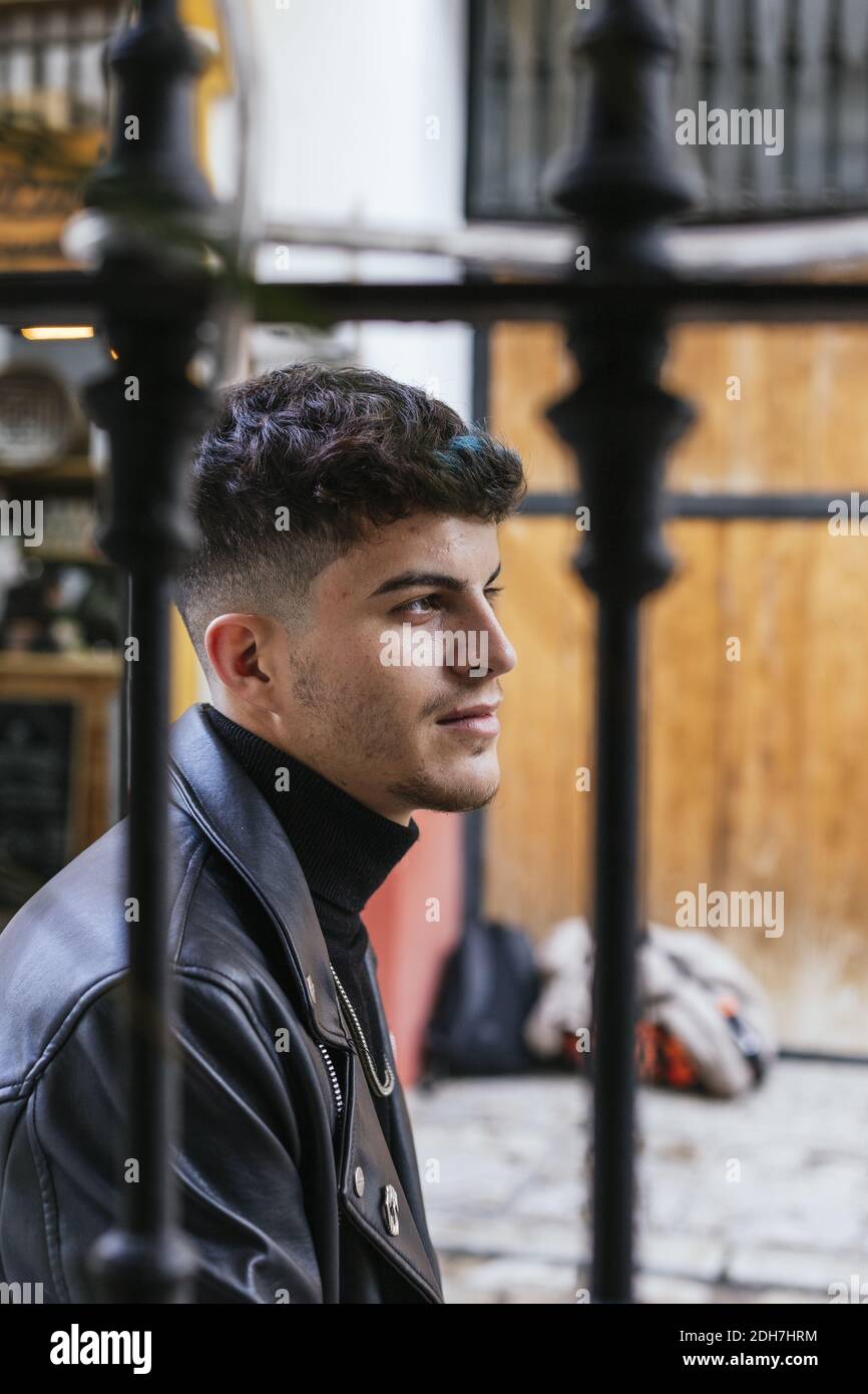 A vertical shot of a stylish young man outdoors behind a fence Stock ...