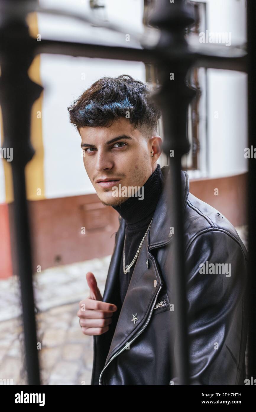 A vertical shot of a stylish young man outdoors behind a fence Stock ...