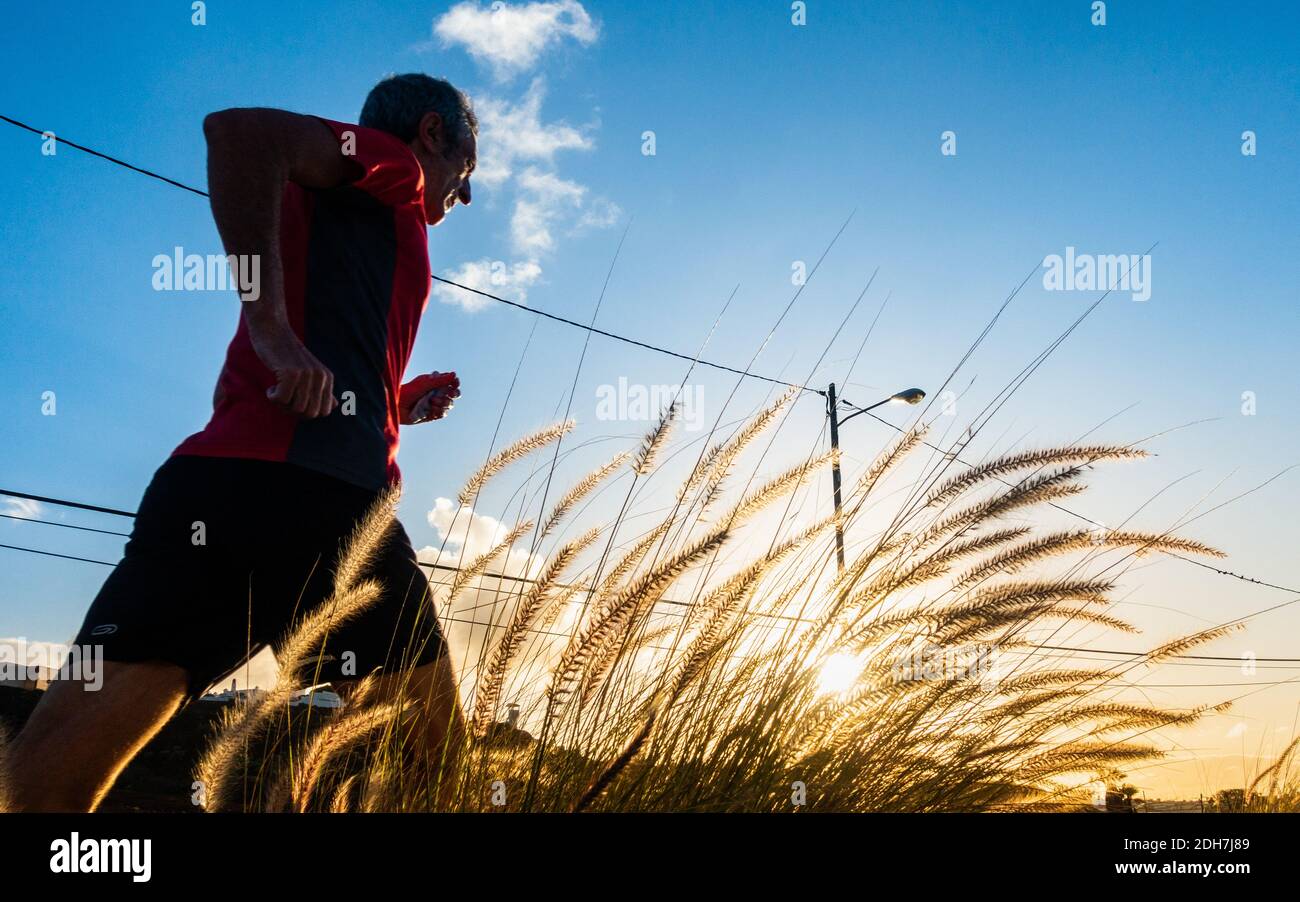60 - 65 year old man running on trail at sunrise. Healthy mature man ...