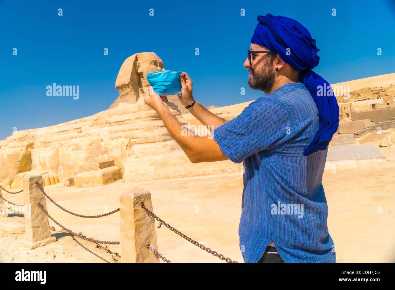 A young man putting on the mask of the face of the Great Sphinx of Giza ...