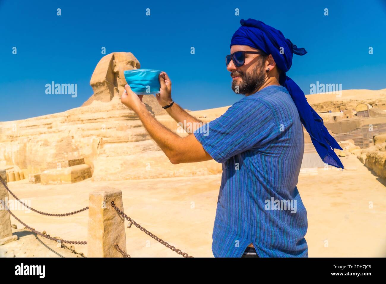 A young man putting on the mask of the face of the Great Sphinx of Giza ...