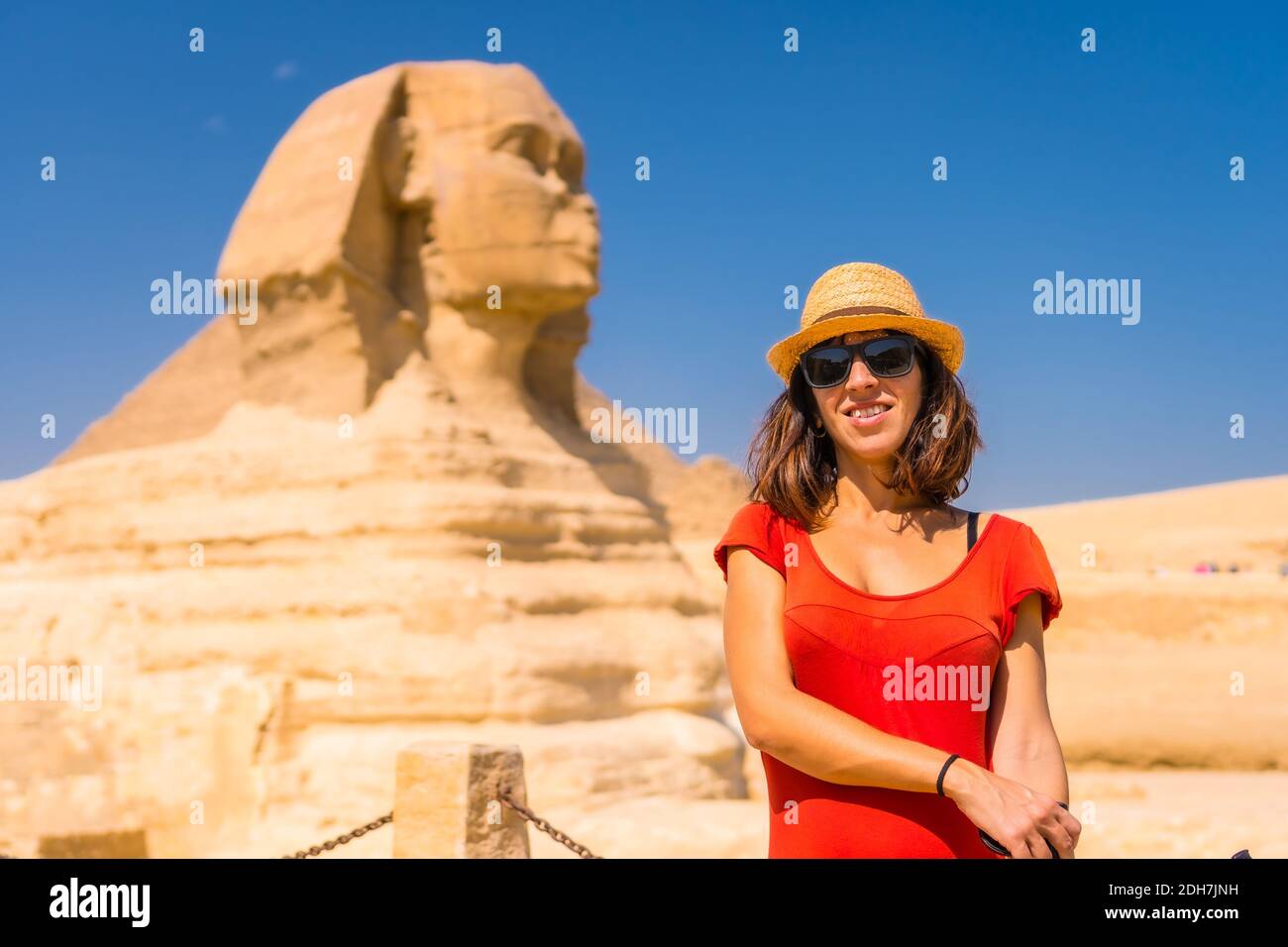 A portrait of a young woman at the Great Sphinx of Giza dressed in red ...