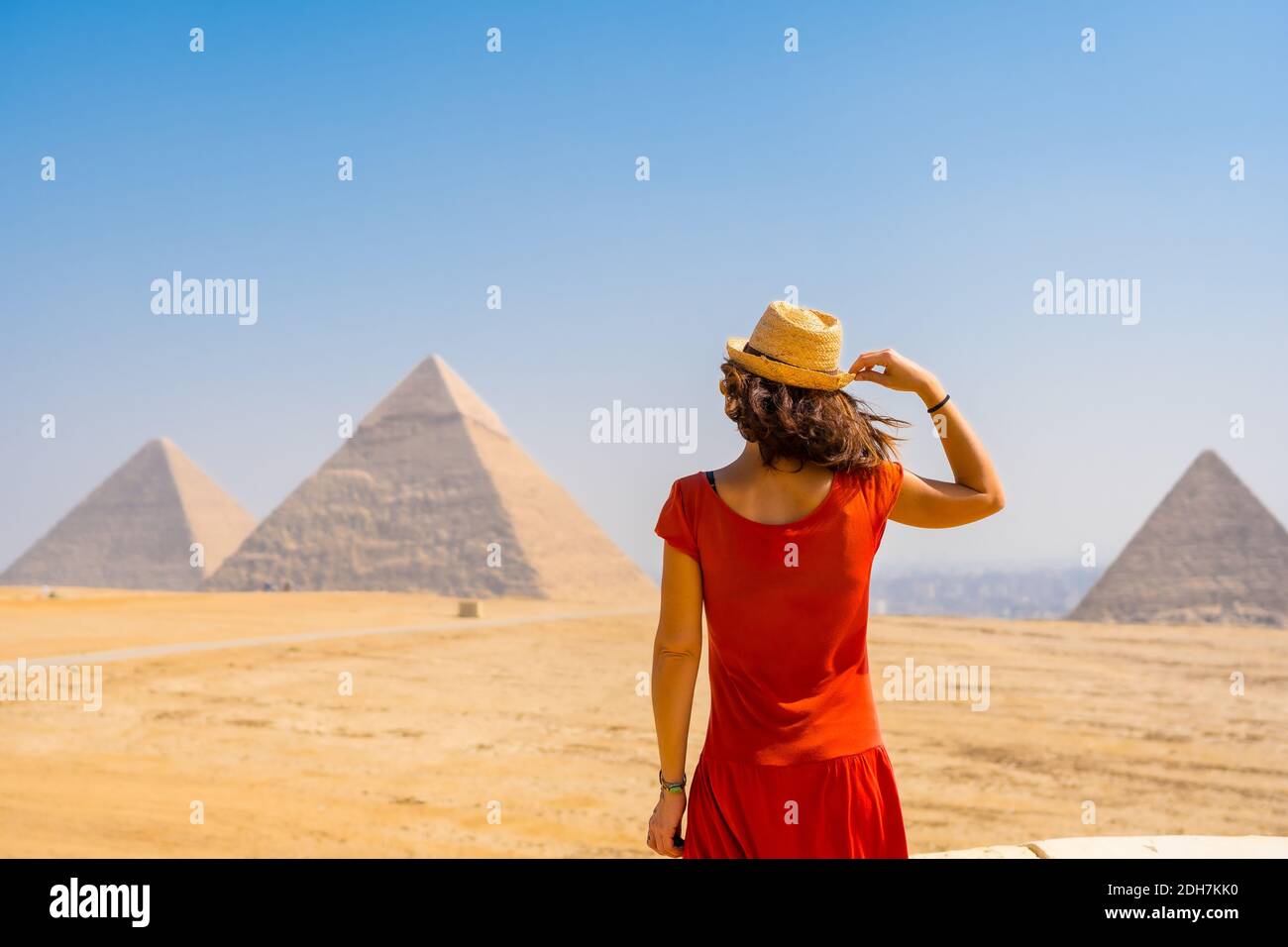 A girl in a red dress looking at the Pyramids of Giza, of Cairo, Egypt ...
