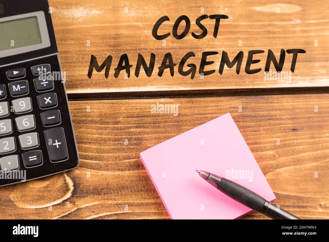 A top view of a calculator with sticky notes and a pen on the desk with ...