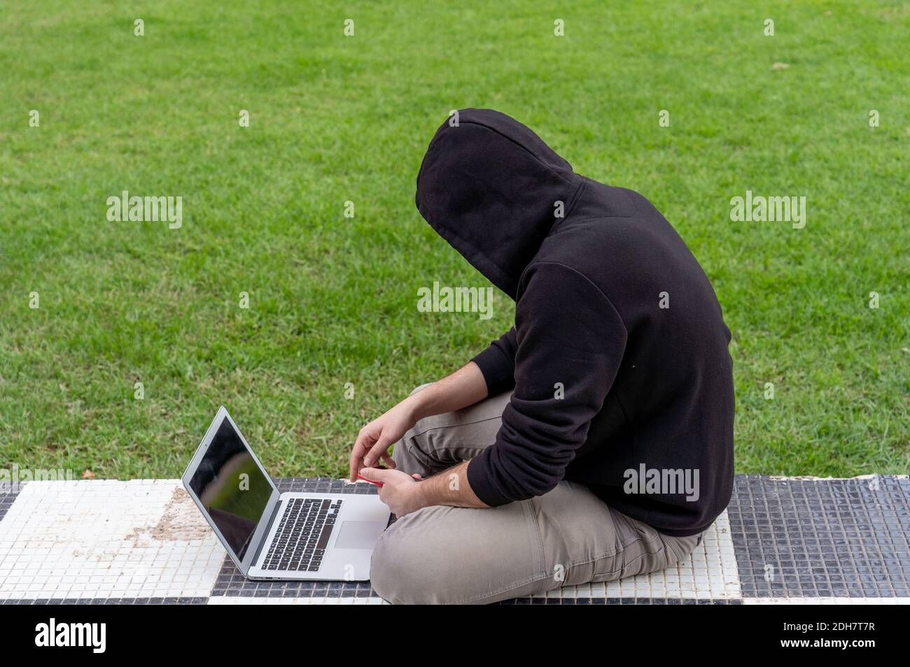 A young man sitting with a bad posture using his laptop and phone Stock ...