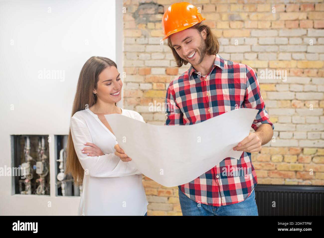 Construction worker in orange helmet and a customer discussing the ...