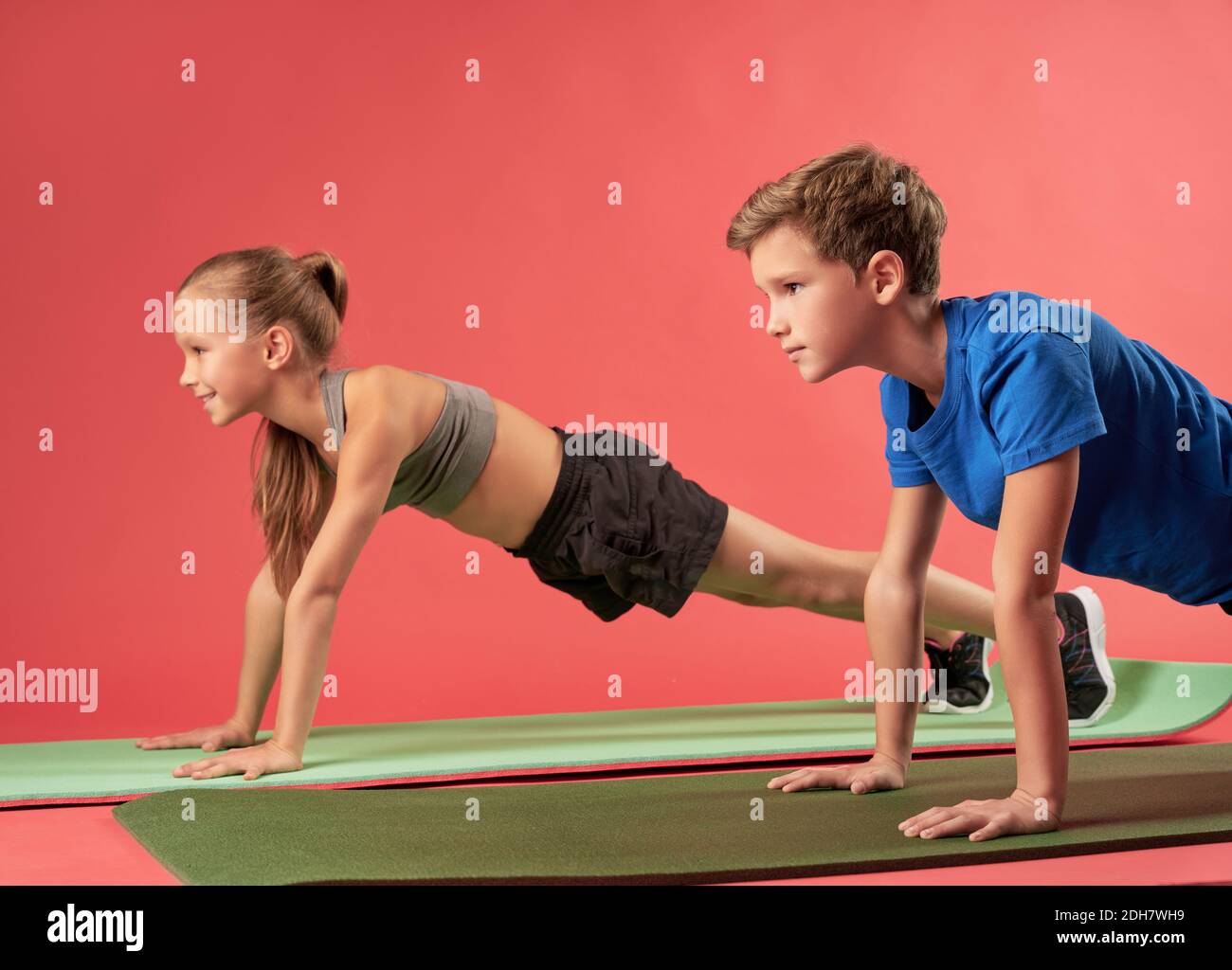 Cute kids in sportswear holding push-up position while doing strength ...