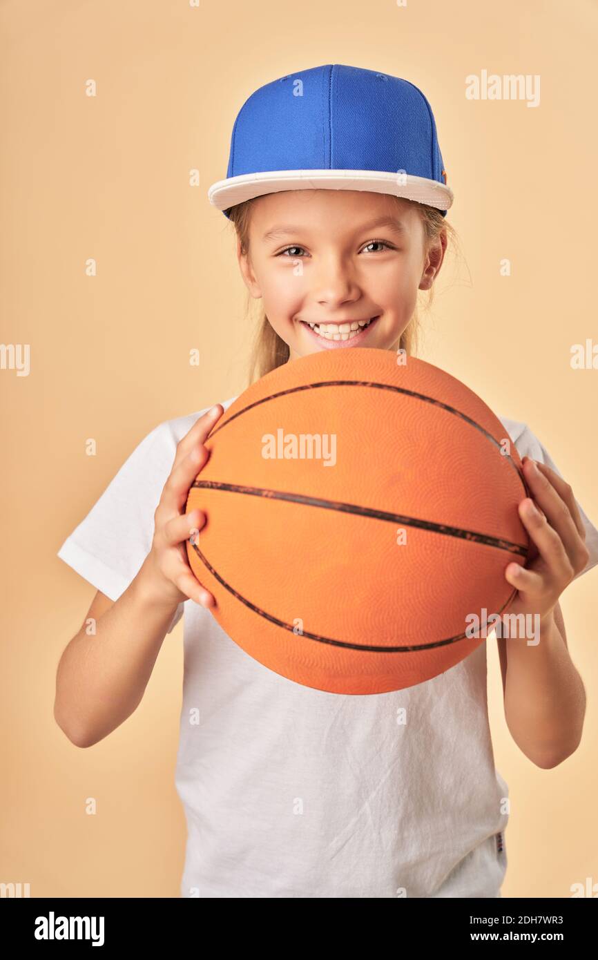 Cute female child basketball player holding game ball and smiling while ...