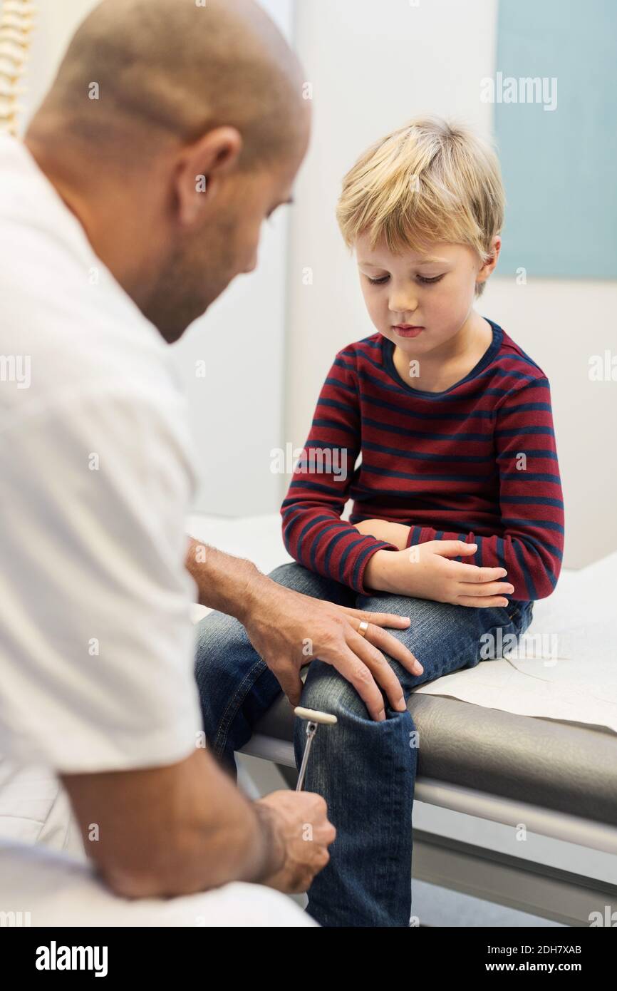 Doctor checking knee reflexes of boy at orthopedic clinic Stock Photo ...