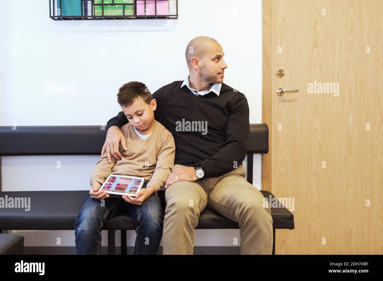 Father and son sitting in waiting room of orthopedic clinic Stock Photo ...