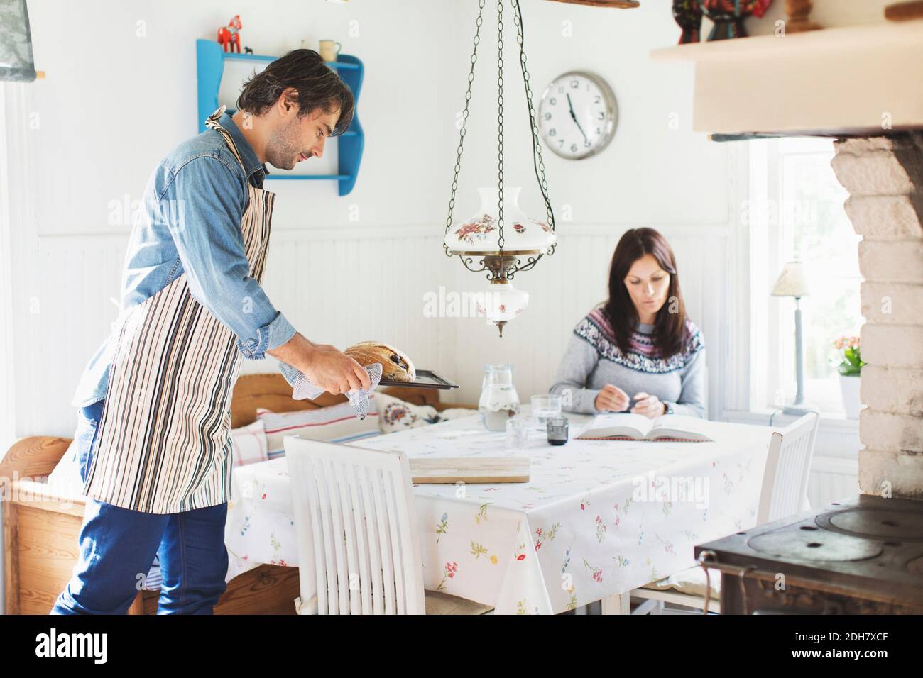 Side view of man serving bread on dining table for woman at home Stock ...