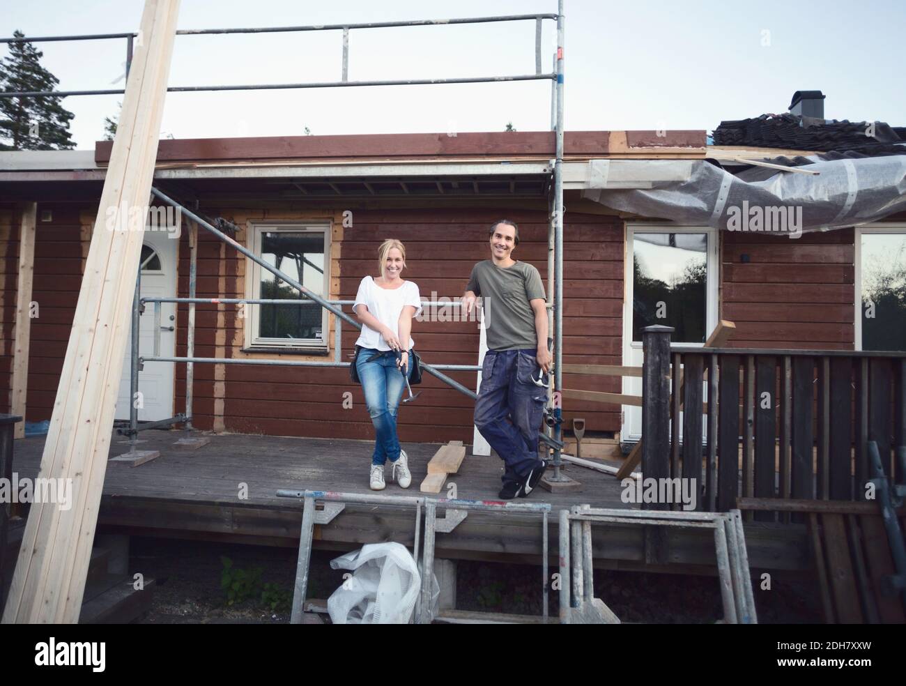 Full length portrait of happy couple leaning on scaffolding of house ...