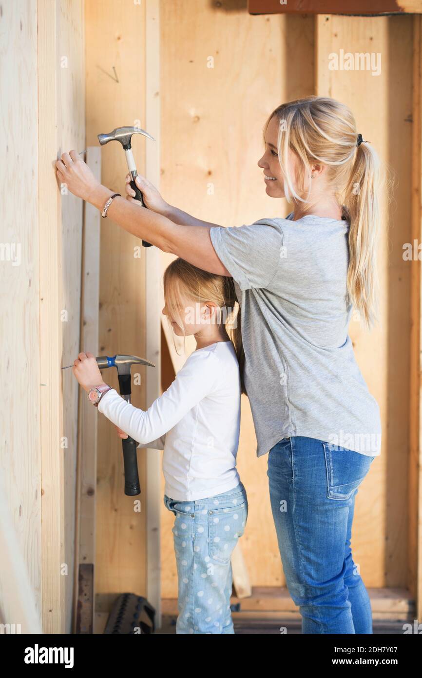 Side view of mother and daughter using hammers at house during home ...