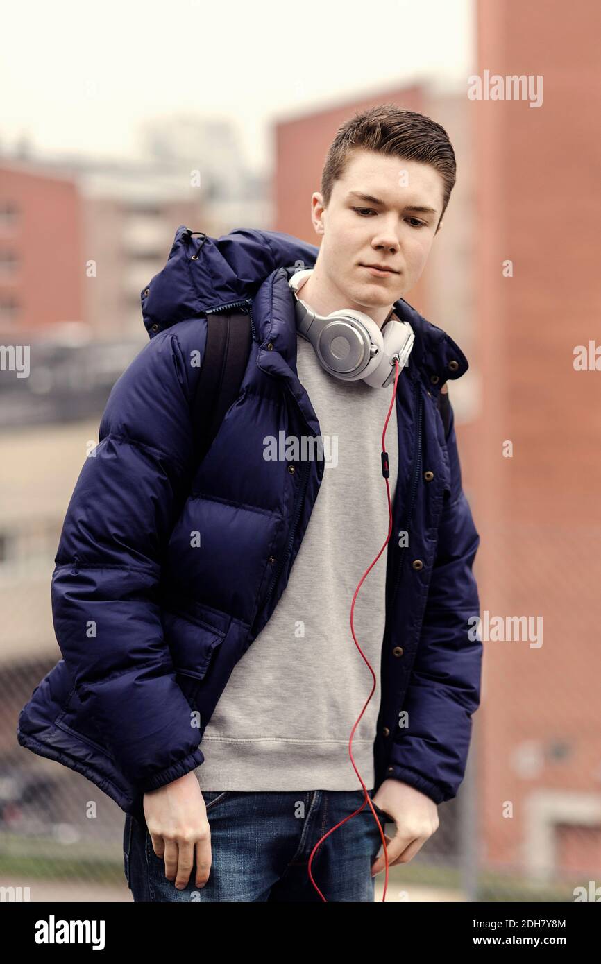 Confident male university student in warm clothing standing outdoors ...