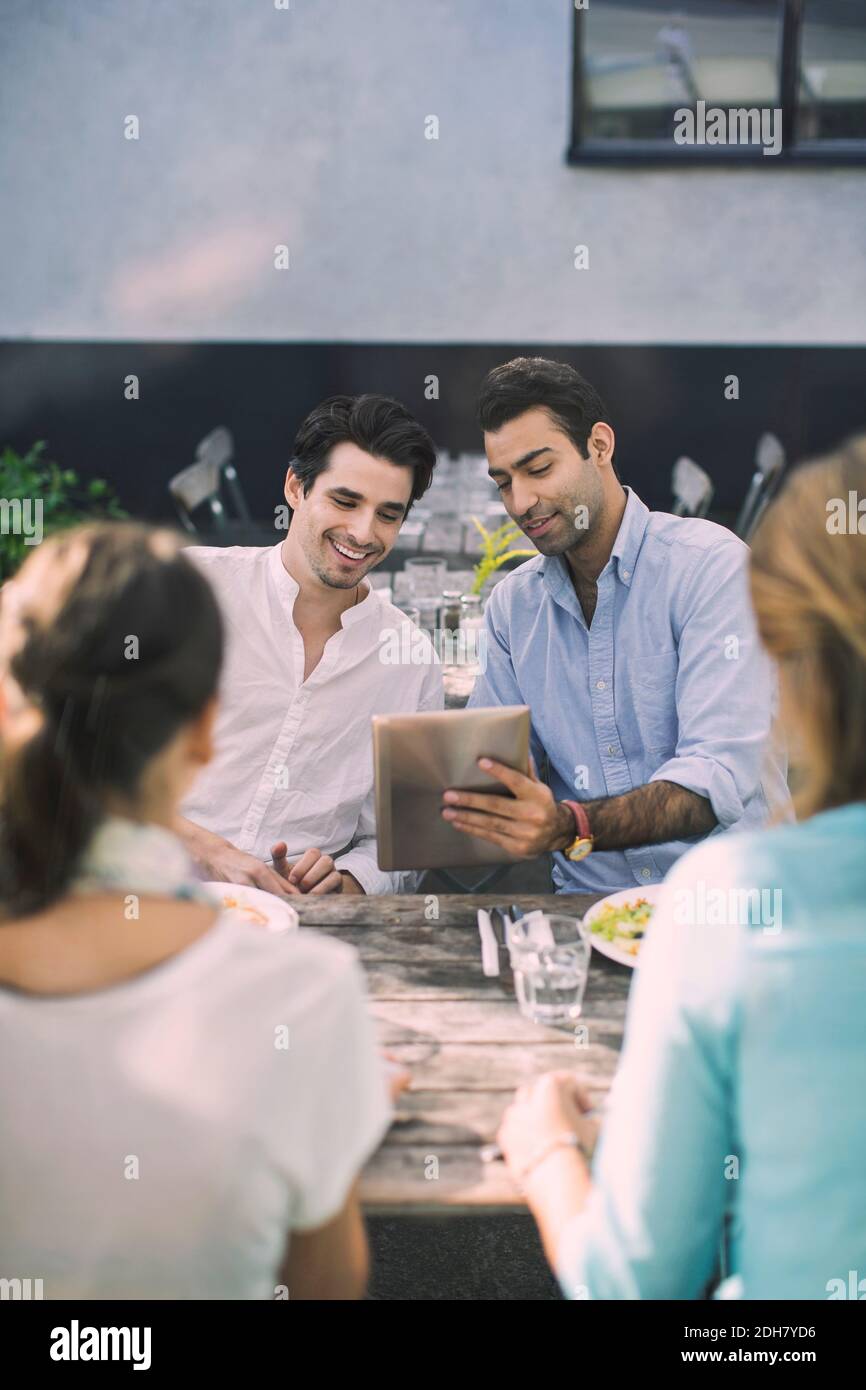 Two men using digital tablet at outdoor cafe Stock Photo - Alamy