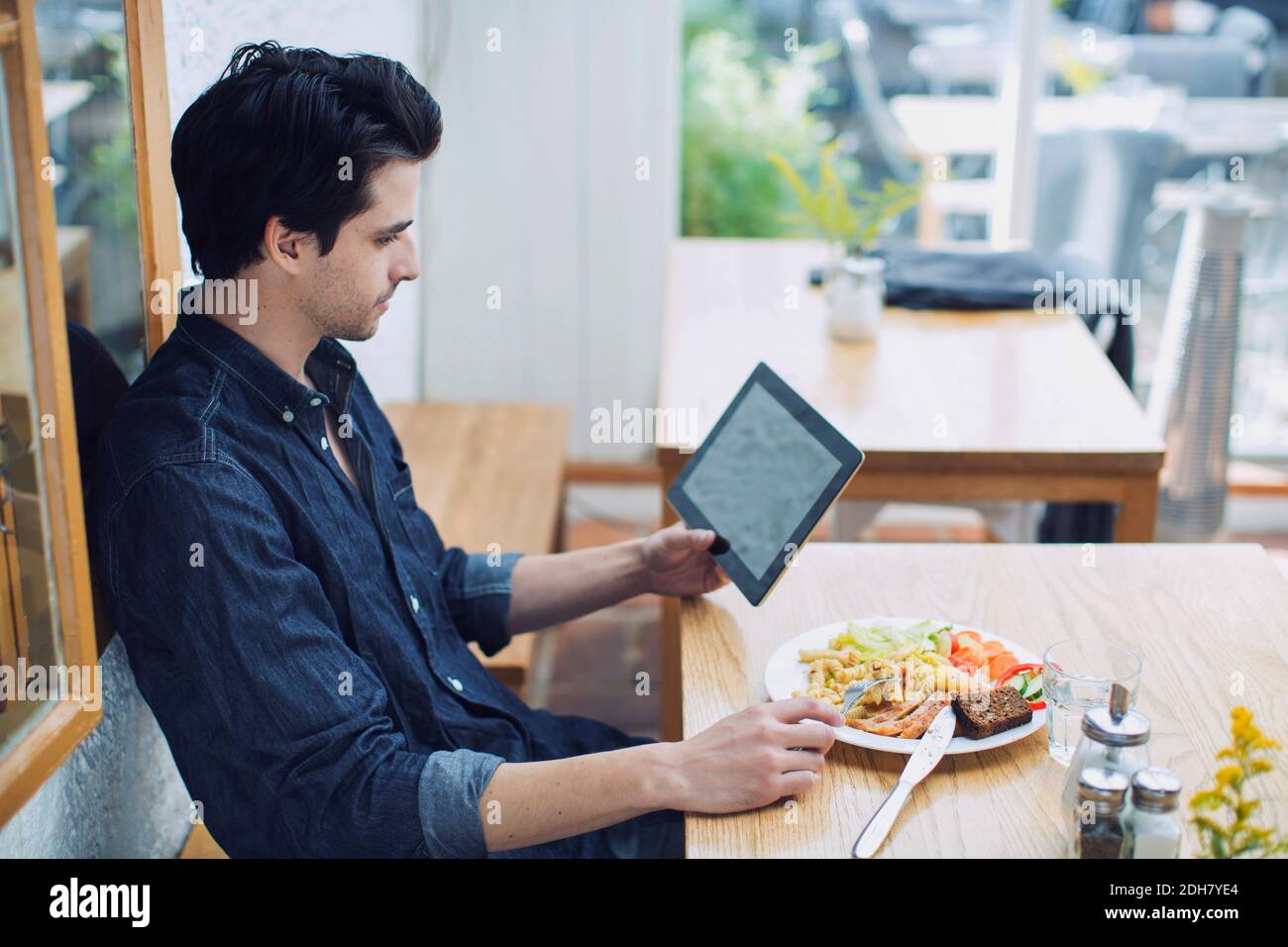 Man using digital tablet while having lunch at cafe Stock Photo - Alamy