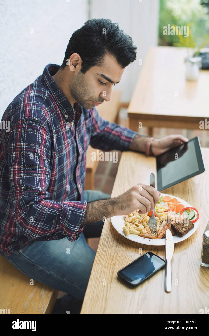 Man using digital tablet while having lunch at restaurant Stock Photo ...