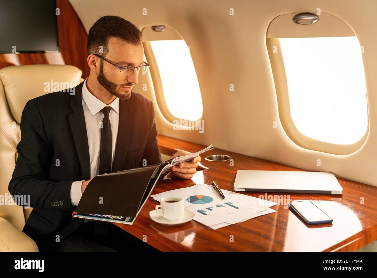 Handsome businessman wearing elegant suit flying on exclusive private ...