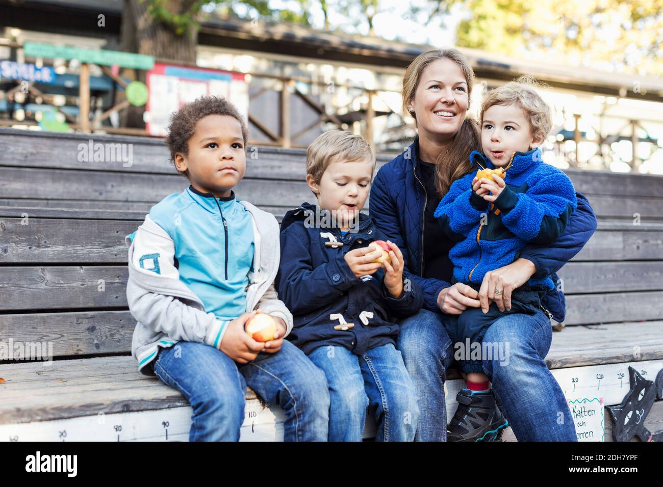 Happy teacher sitting with children outside kindergarten Stock Photo ...