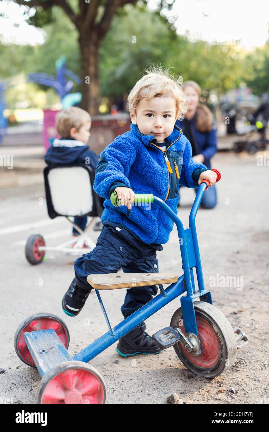 Portrait of boy playing with tricycle on playground Stock Photo - Alamy