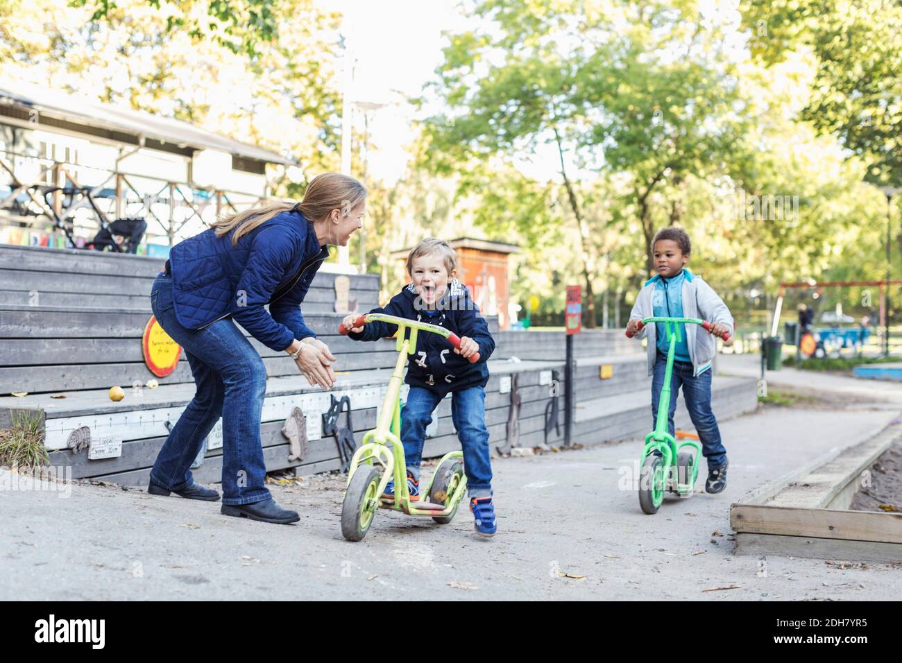Teacher motivating children on push scooters during race Stock Photo ...
