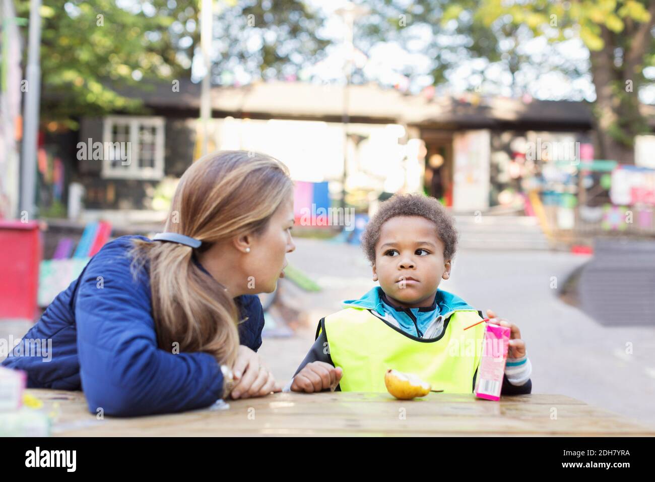 Angry teacher looking at student holding juice box outside kindergarten ...