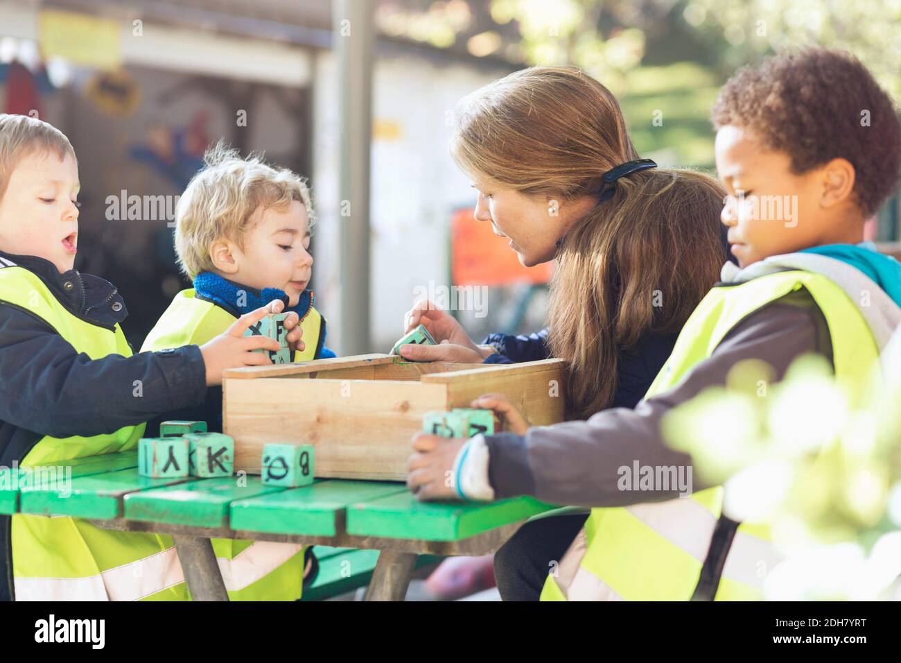 Teacher and children playing with blocks outside Stock Photo - Alamy