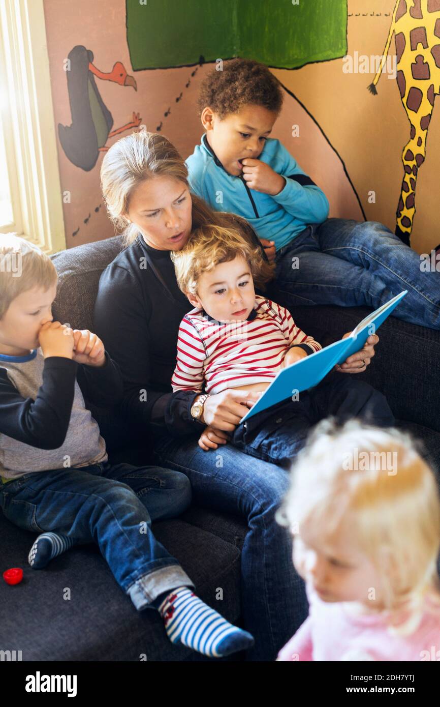 High angle view of teacher telling story to children in kindergarten ...