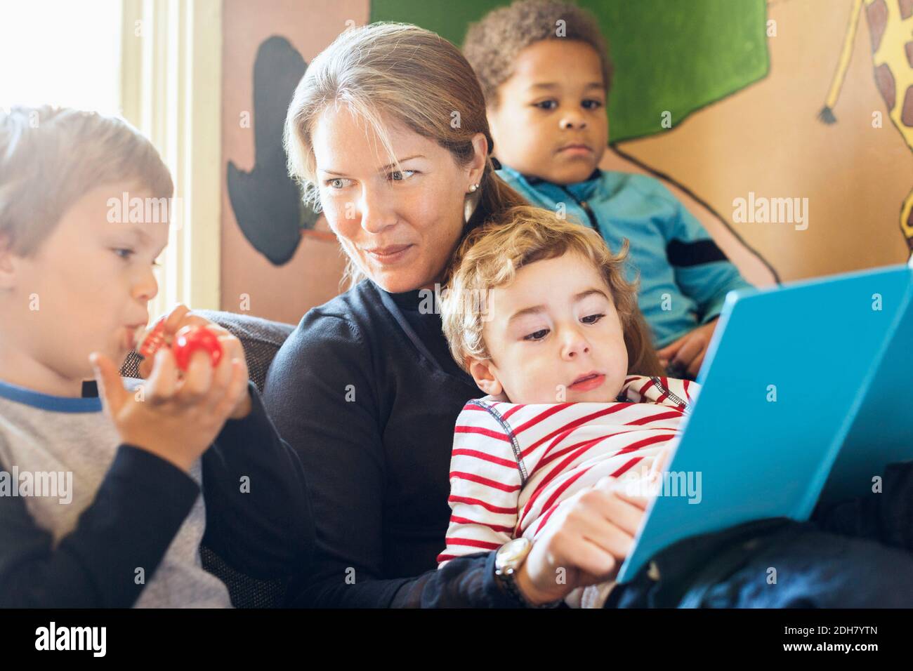 Female teacher telling story to children in kindergarten Stock Photo ...