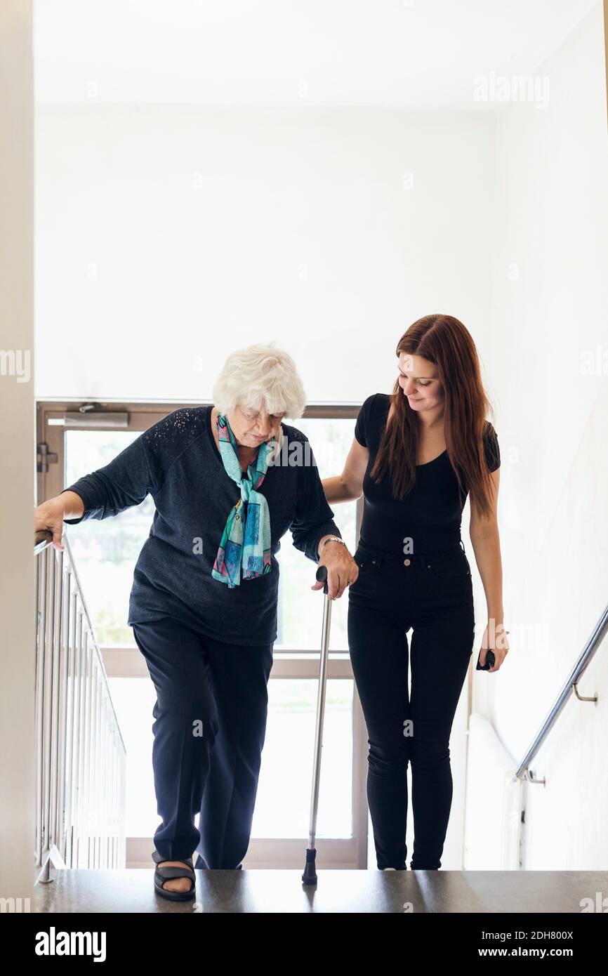 Young woman helping grandmother to climb steps Stock Photo - Alamy