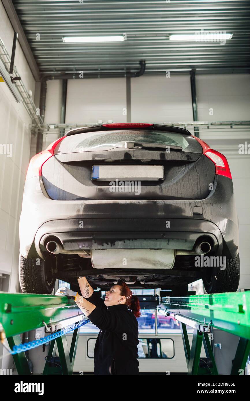 Side view of female mechanic repairing car on hydraulic lift Stock ...