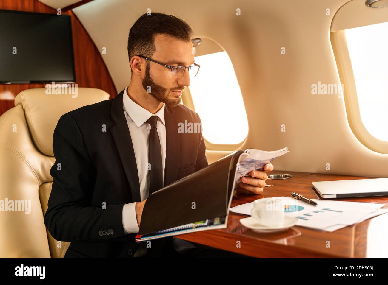 Handsome businessman wearing elegant suit flying on exclusive private ...