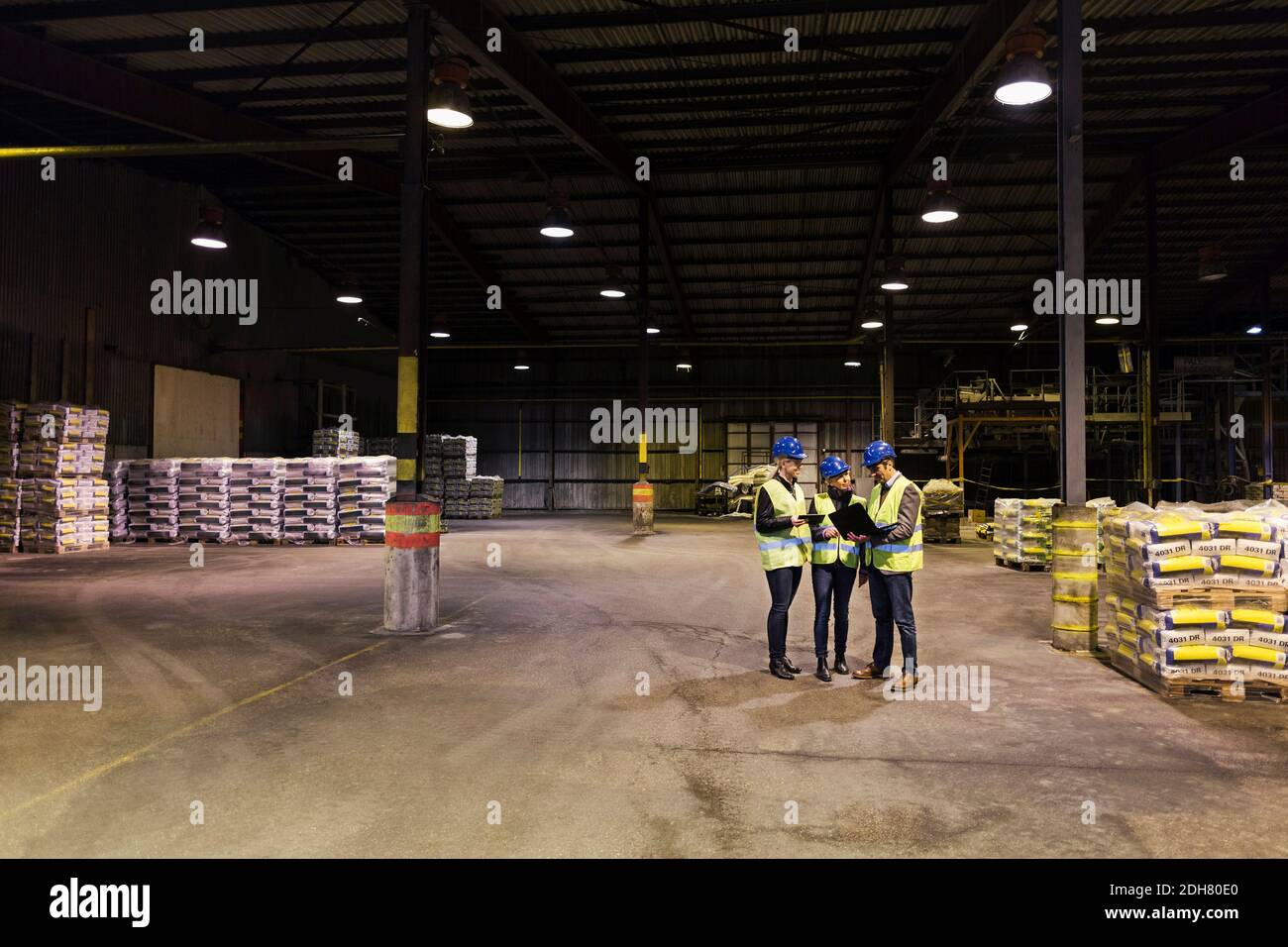 Full length of manual workers using technologies in cement warehouse ...