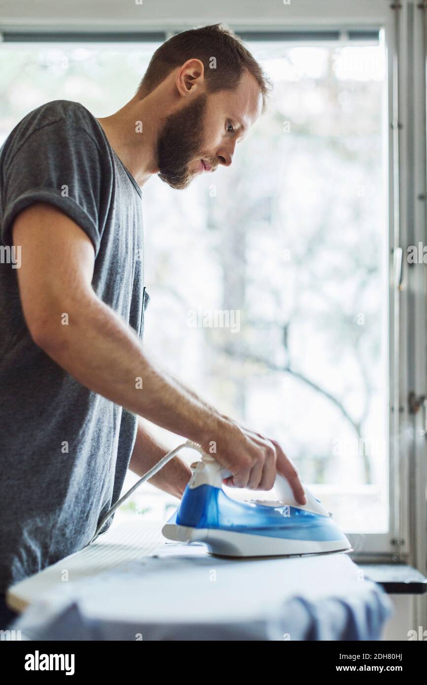 Young man ironing laundry hi-res stock photography and images - Alamy