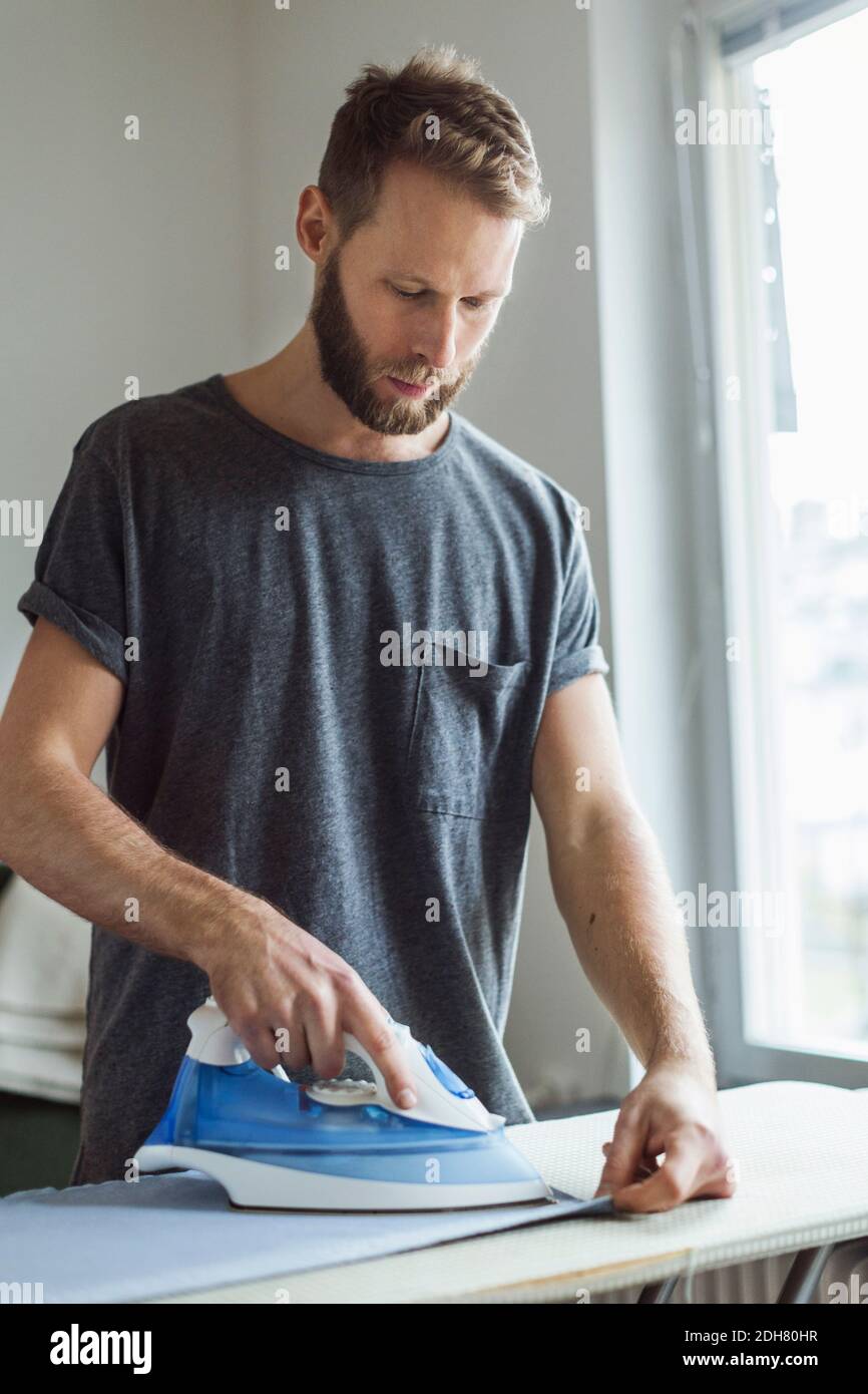 Young man ironing laundry hi-res stock photography and images - Alamy