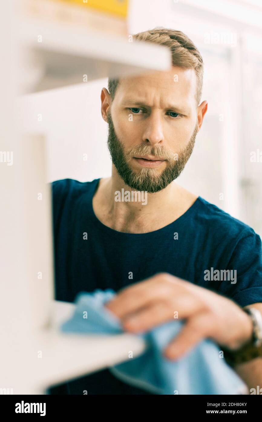 Man cleaning shelf with rag Stock Photo - Alamy