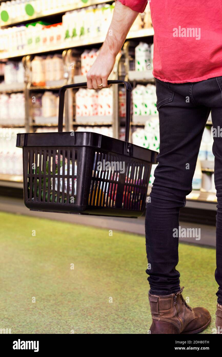 Low section of man carrying basket in supermarket Stock Photo - Alamy